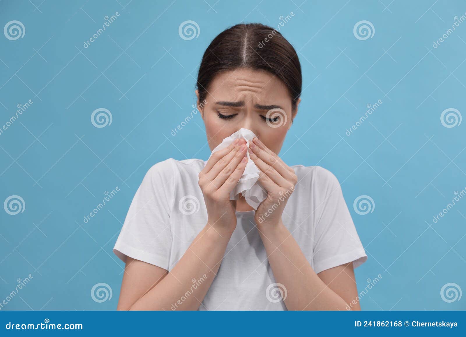 Woman Blowing Nose on Light Blue Background. Cold Symptoms Stock Photo ...