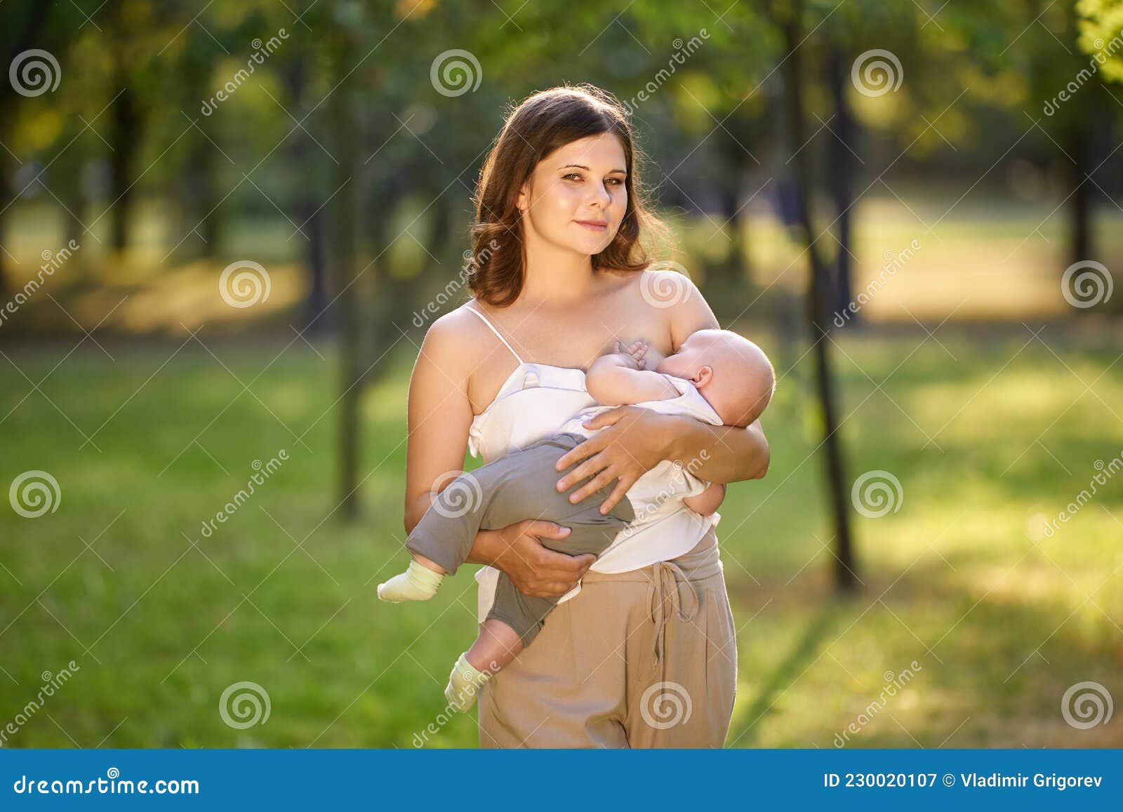 Breastfeeding In Public Park By Young Mother Outdoors Stock Image