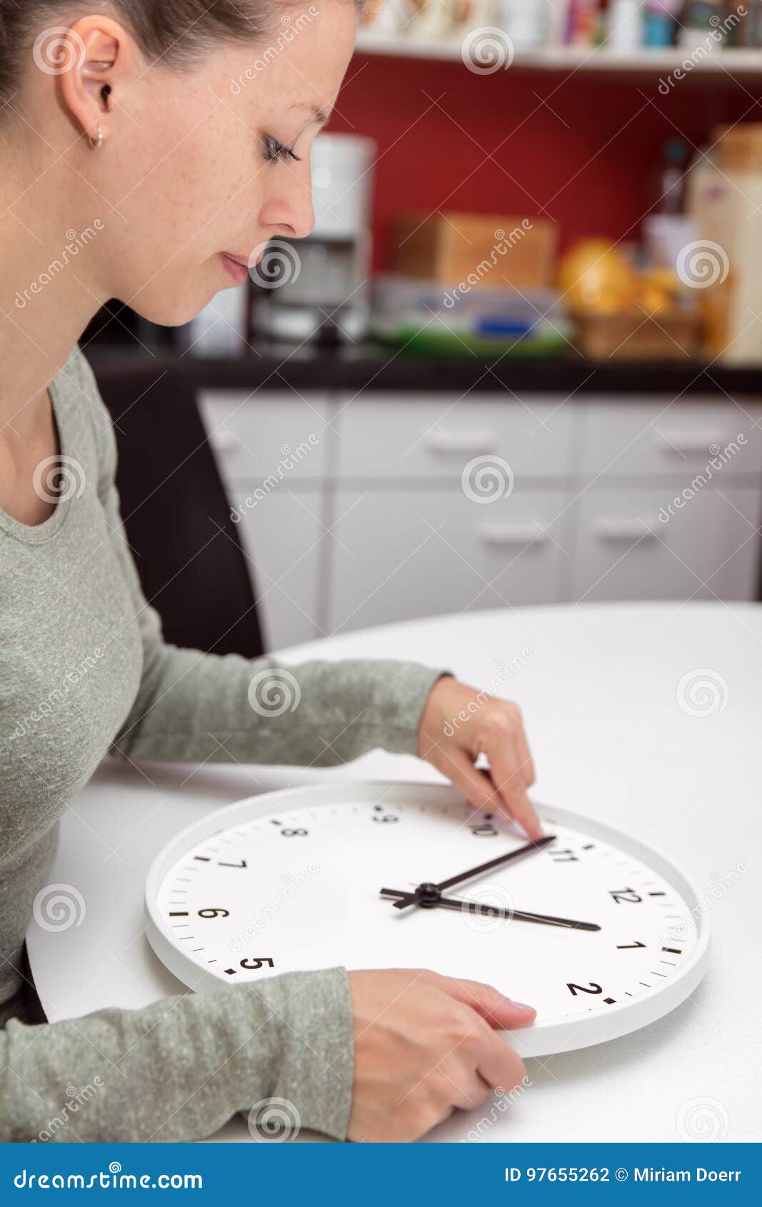 A Woman Changes the Time on a Clock Stock Photo - Image of kitchen ...