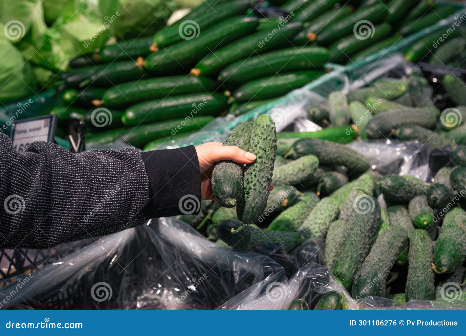 A Woman Chooses Cucumbers at a Grocery Store. Stock Photo - Image of ...