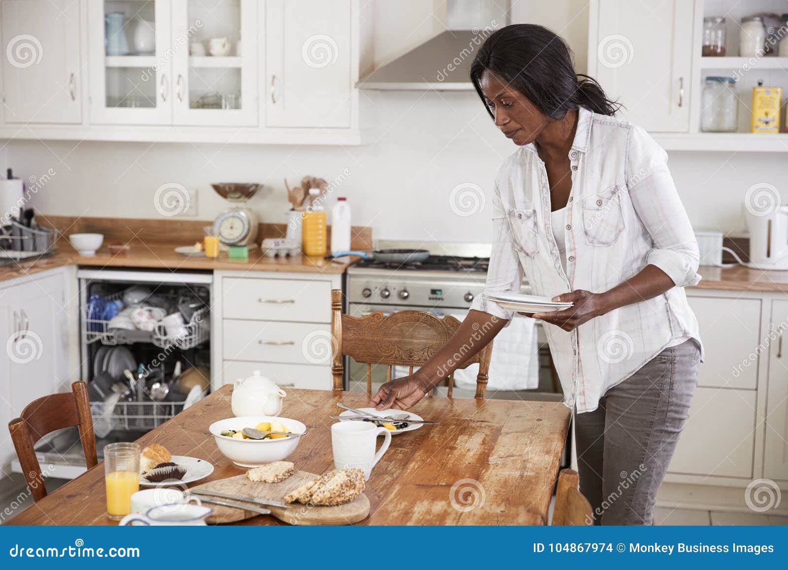 Woman Clearing Breakfast Table and Loading Dishwasher Stock Photo ...