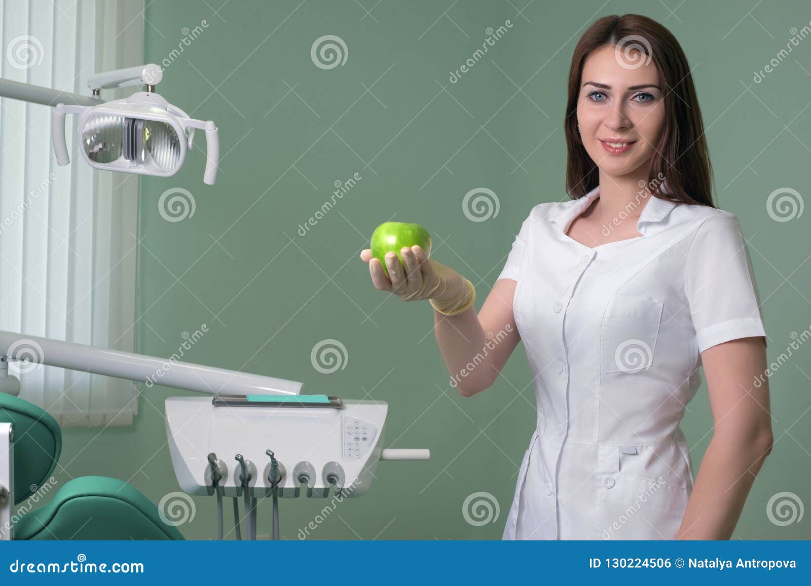 Woman Dentist Doctor In The Dental Office Holding A Green Apple Stock