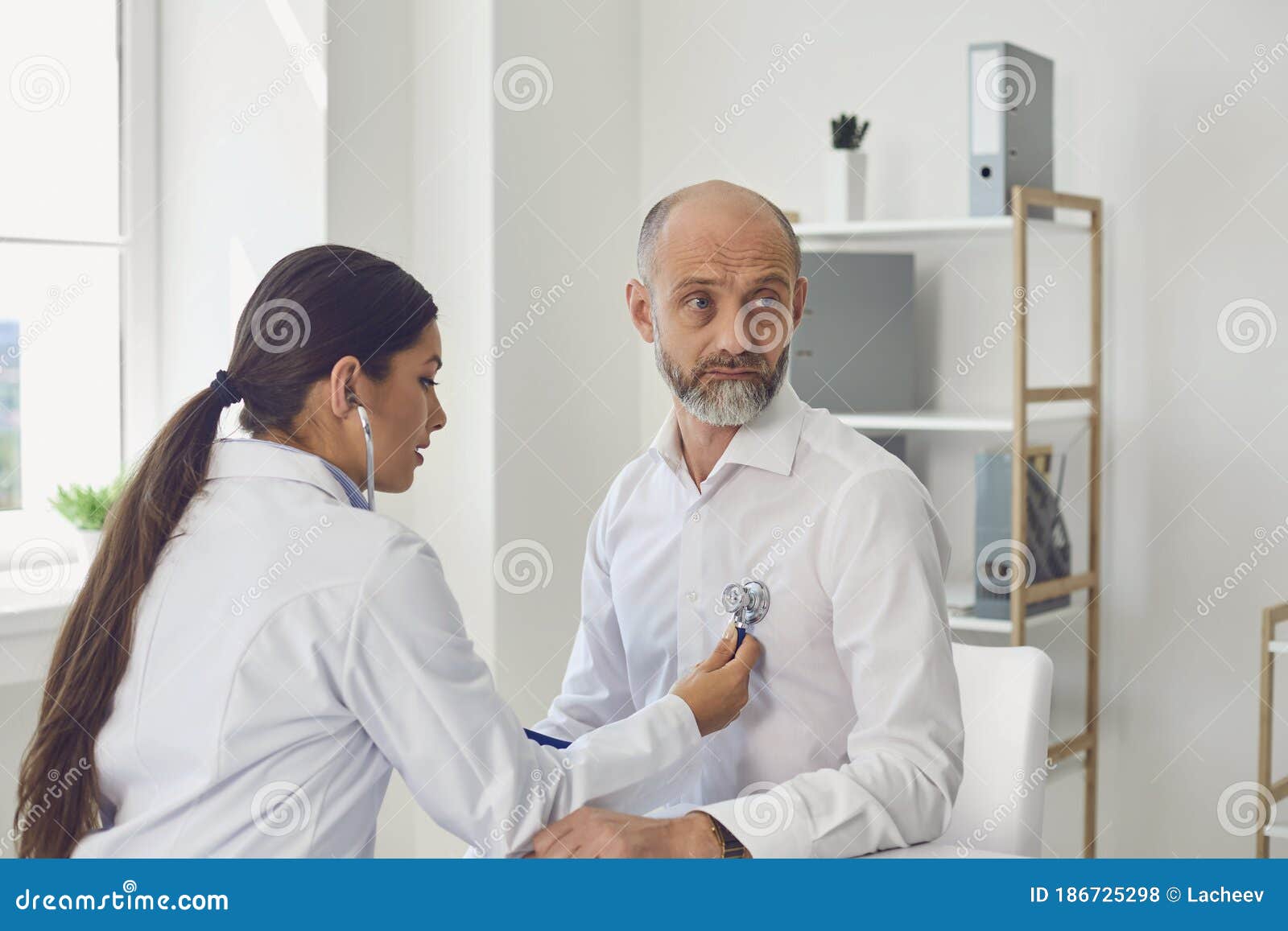 Woman Doctor Cardiologist Listens With Stethoscope To Patient Senor Man