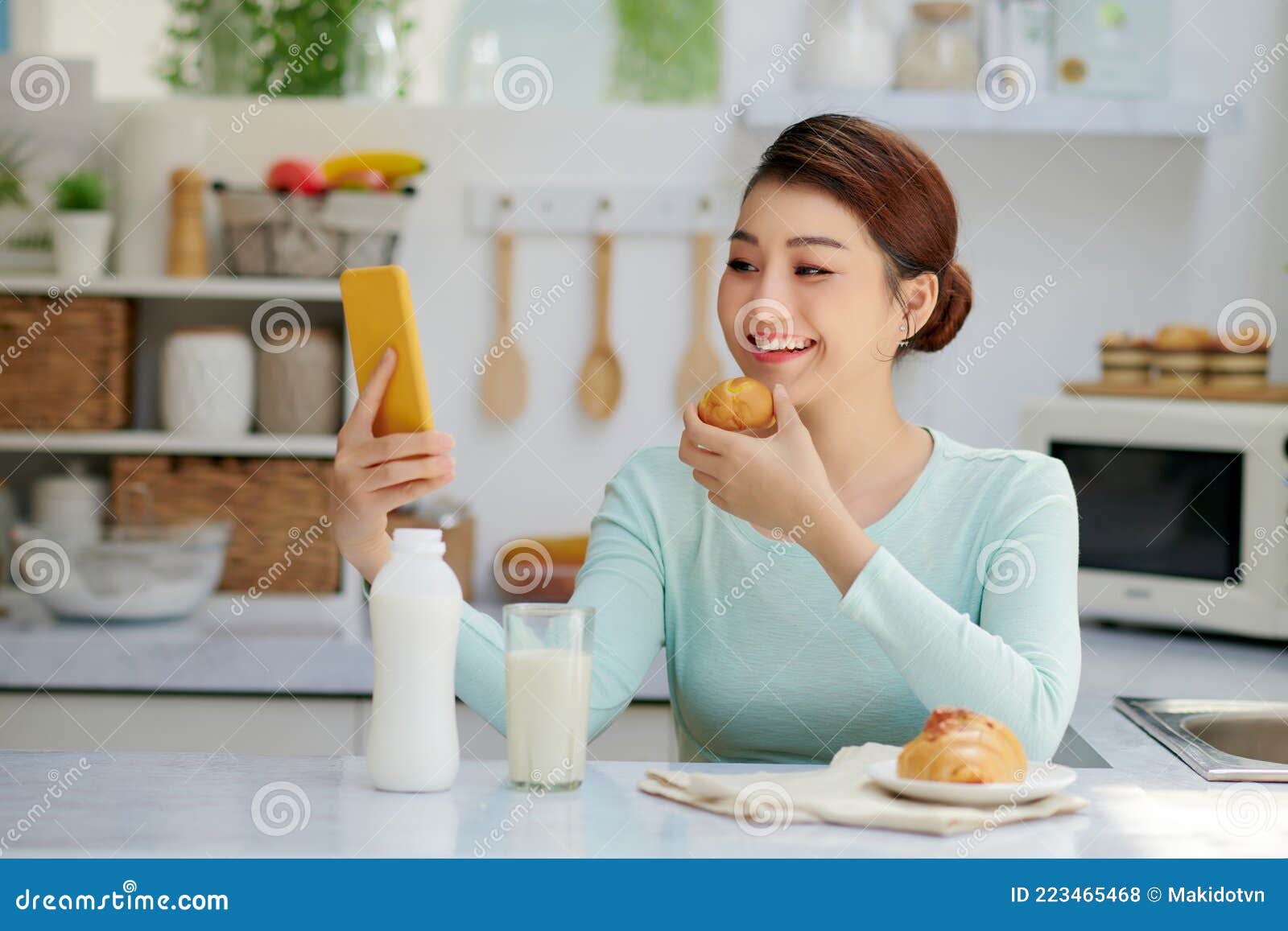 Woman Eating Breakfast Whilst Using Mobile Phone Stock Photo - Image of ...