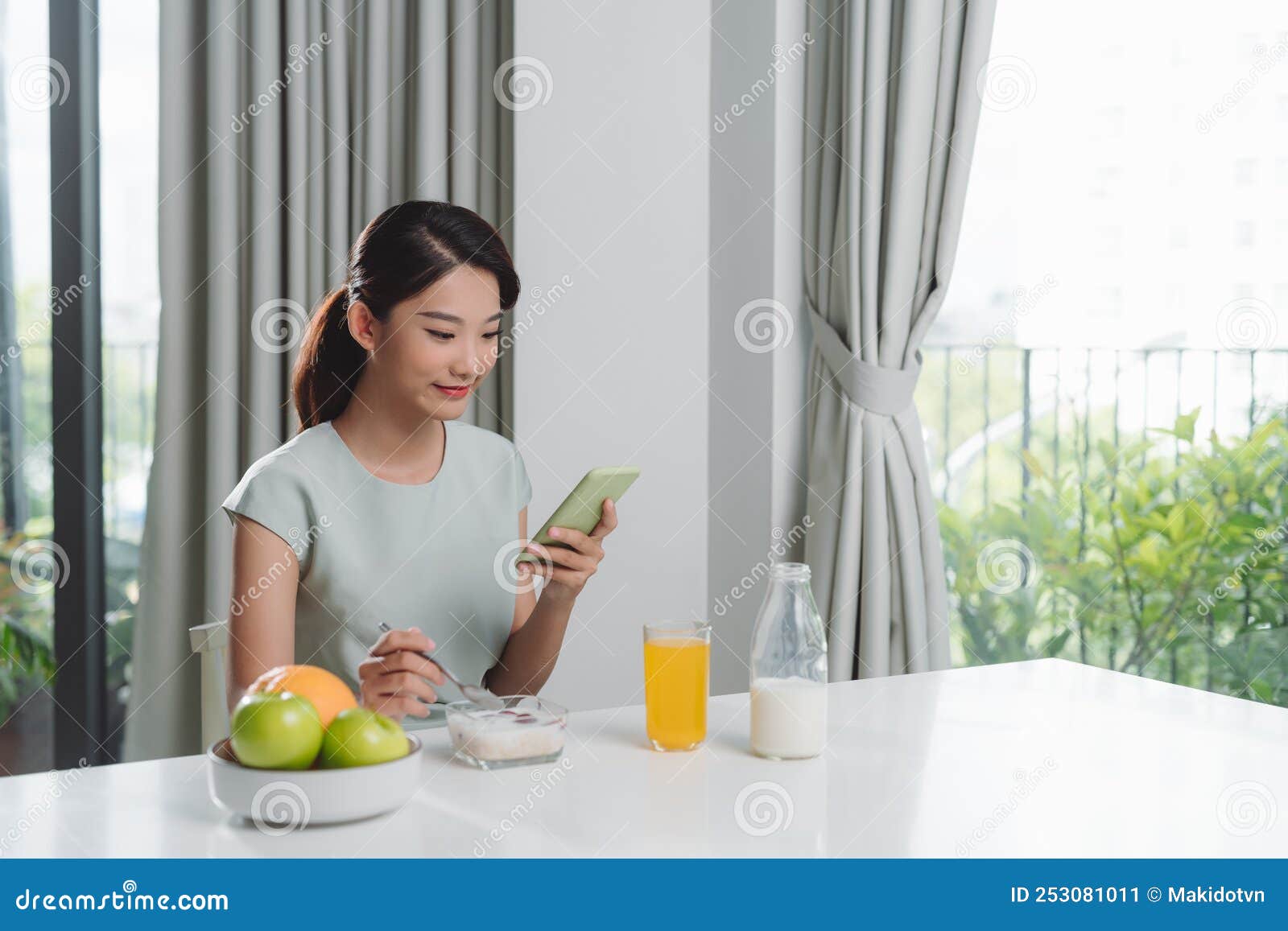 Woman Eating Breakfast Whilst Using Mobile Phone Stock Image - Image of ...