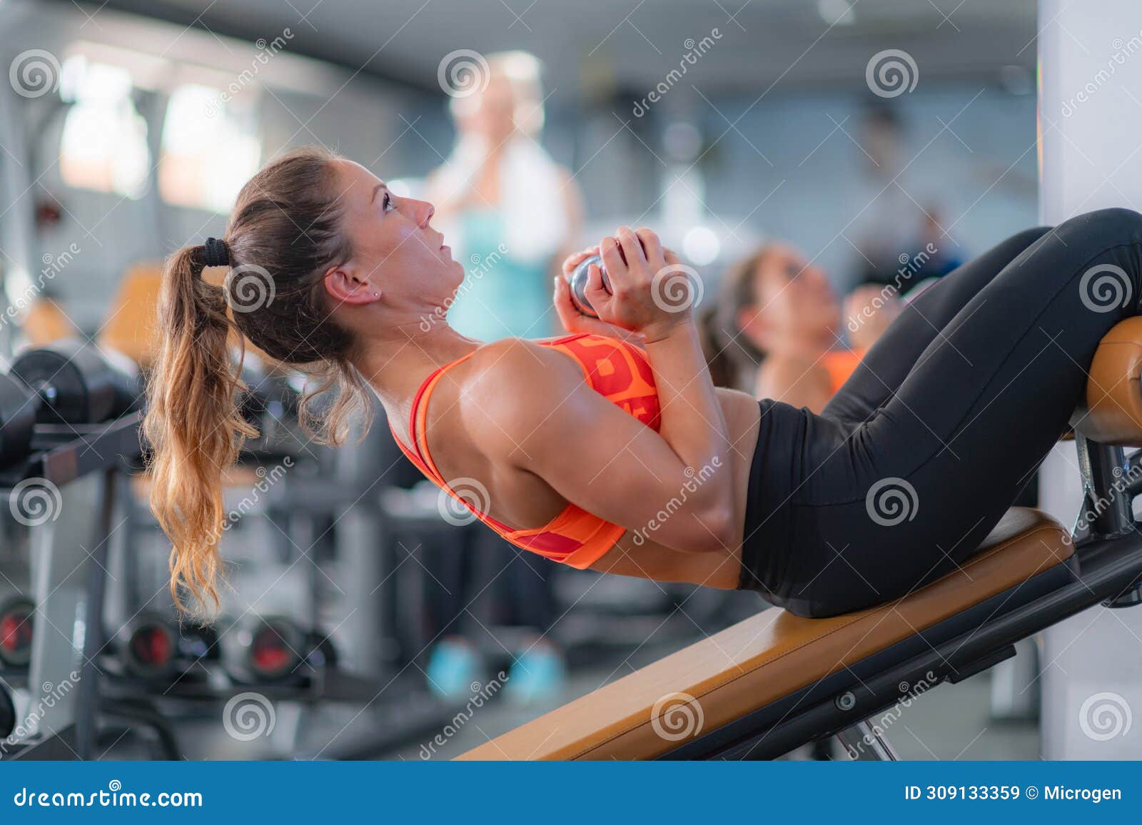 A Woman Engages in Dynamic Sit-ups Using a Dumbbell for Effective Core ...