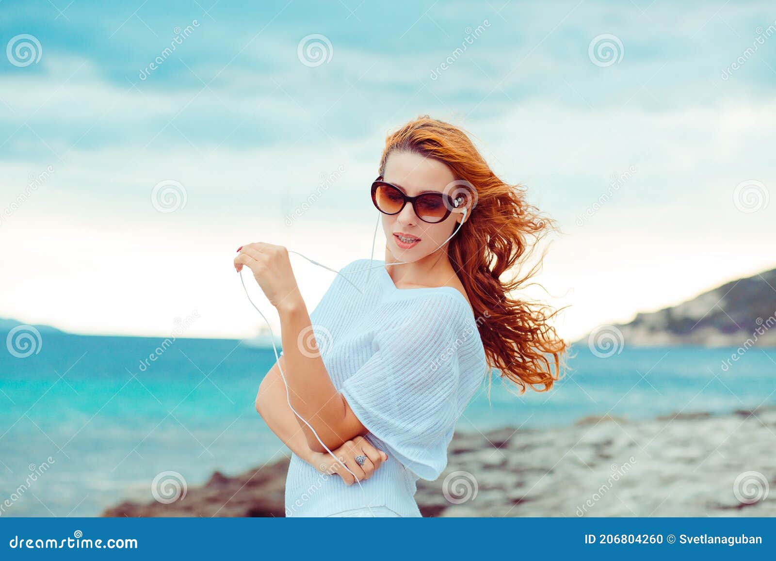 Woman Enjoying Her Summer Vacation On The Beach While Listening To