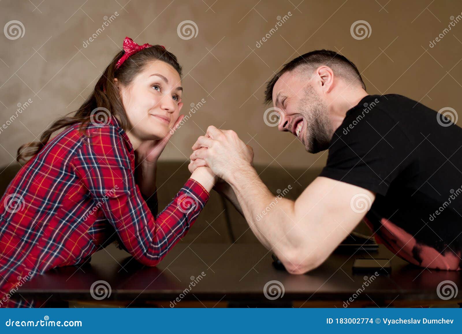 A Woman Enjoys An Easy Fight In Arm Wrestling With Her Husband At Home