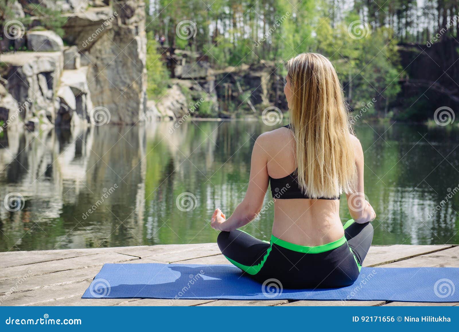 Woman Exercising And Sitting In Yoga Lotus Position While Meditating