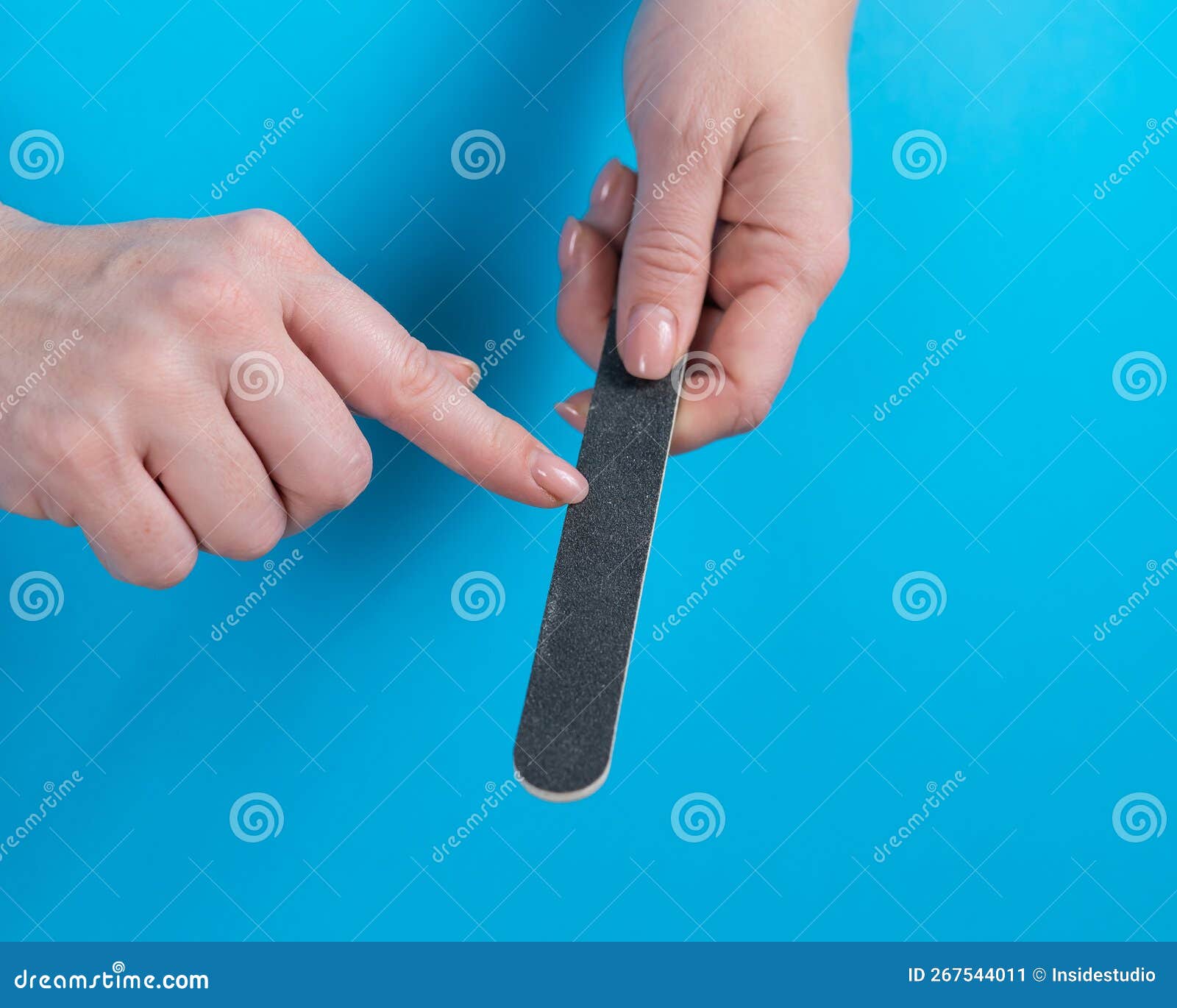 Woman Filing Her Nails on a Blue Background. Stock Image - Image of ...