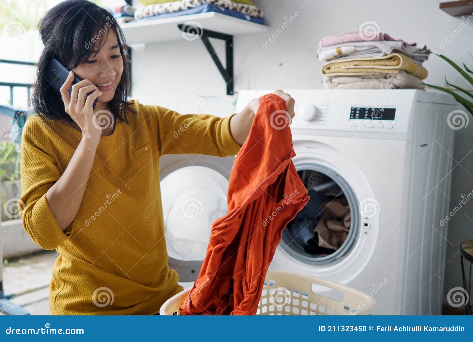 Woman in Front of the Washing Machine Using Phone Stock Photo - Image ...
