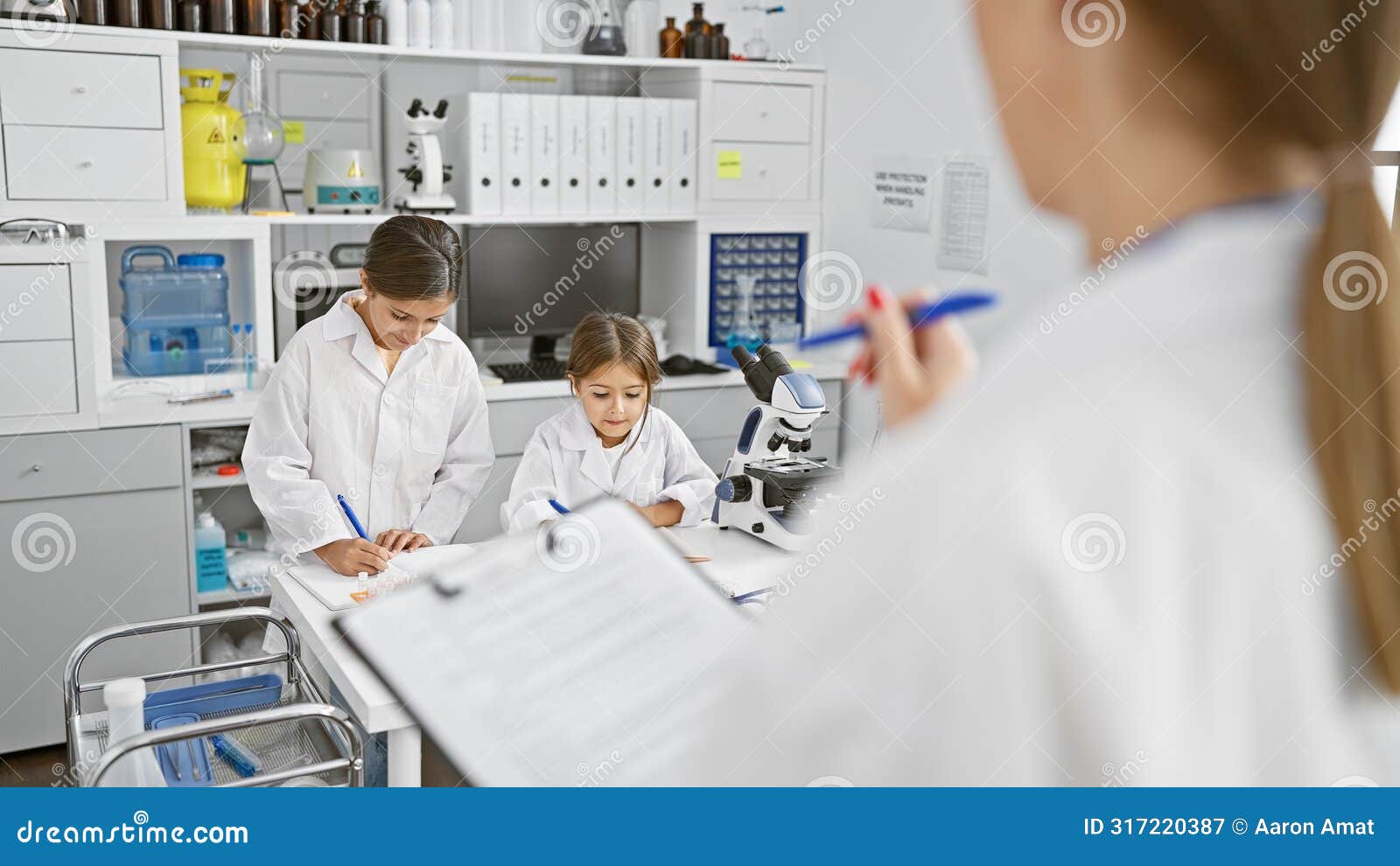 Woman and Girls in Lab Coats Studying with Microscope in Science ...