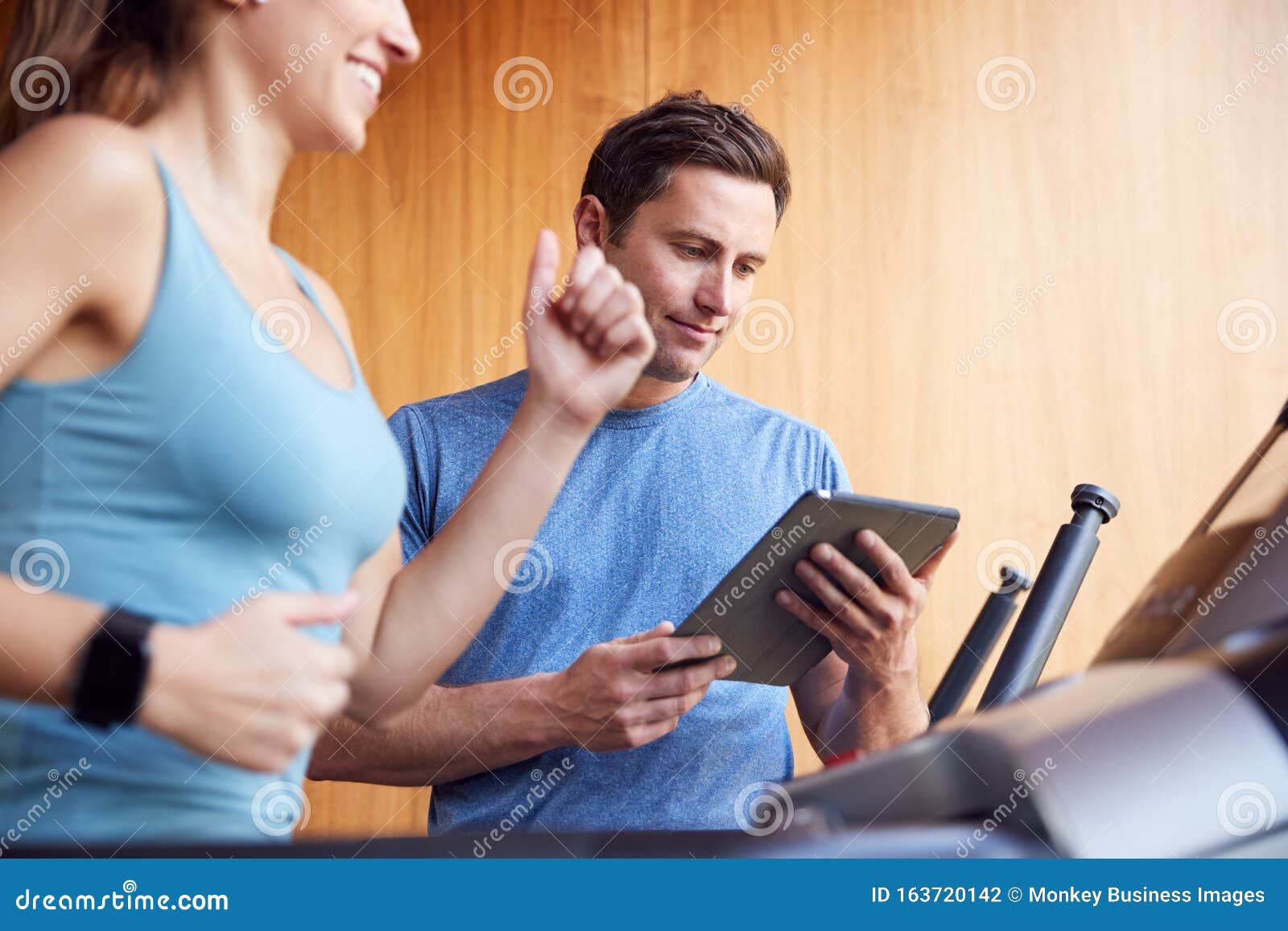 Woman in Gym with Personal Trainer Analysing Performance Using Smart ...