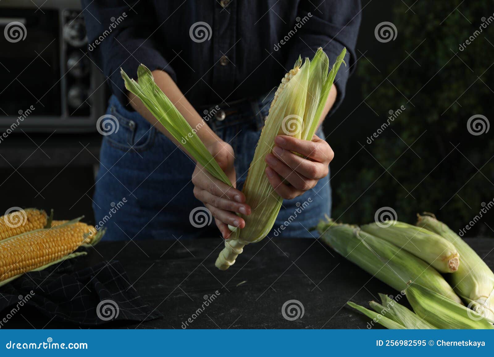 Woman Husking Corn Cob at Black Table, Closeup Stock Image - Image of ...
