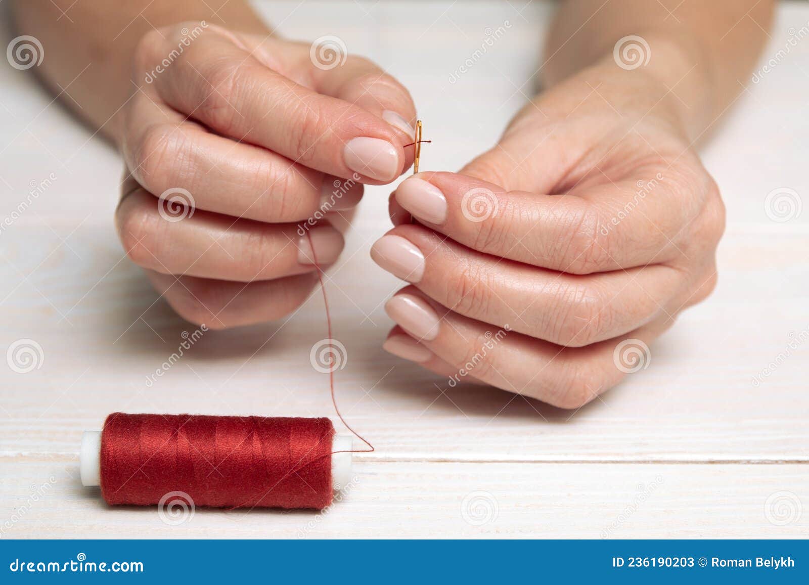 A Woman Inserts a Red Thread into a Needle. Stock Image - Image of ...