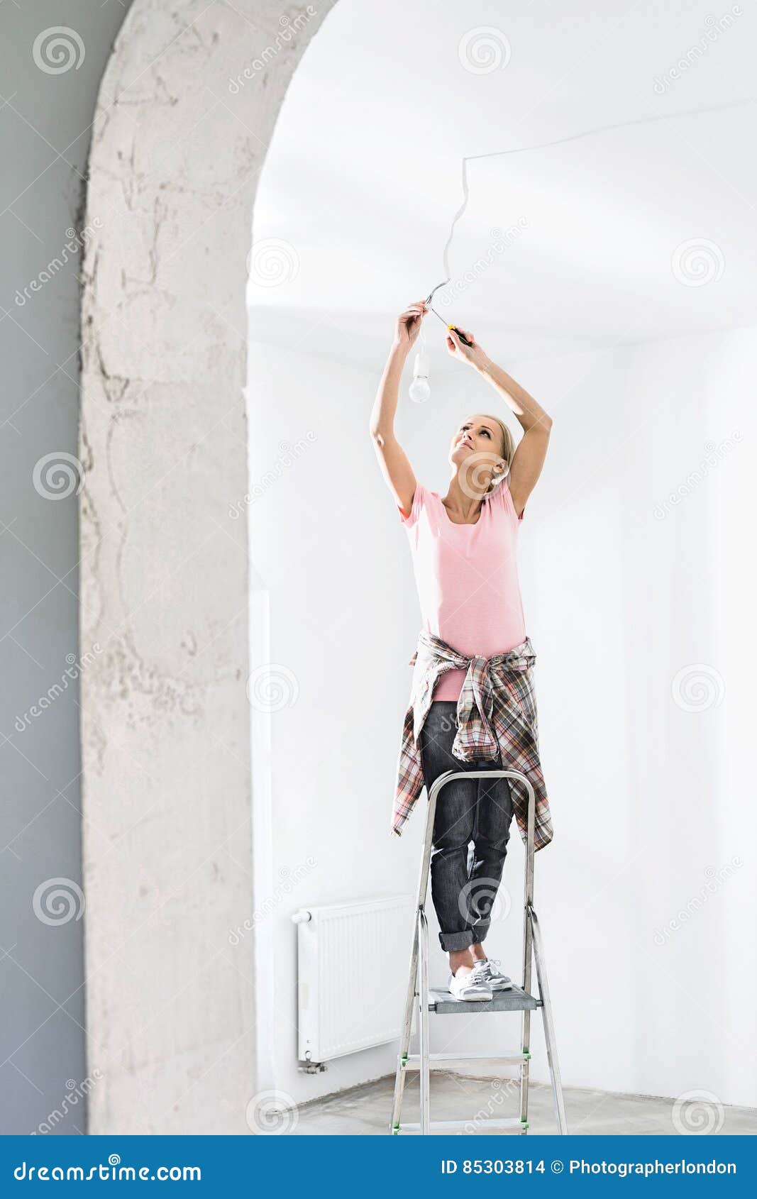 Woman on Ladder Fitting Light Bulb in New House Stock Photo - Image of ...