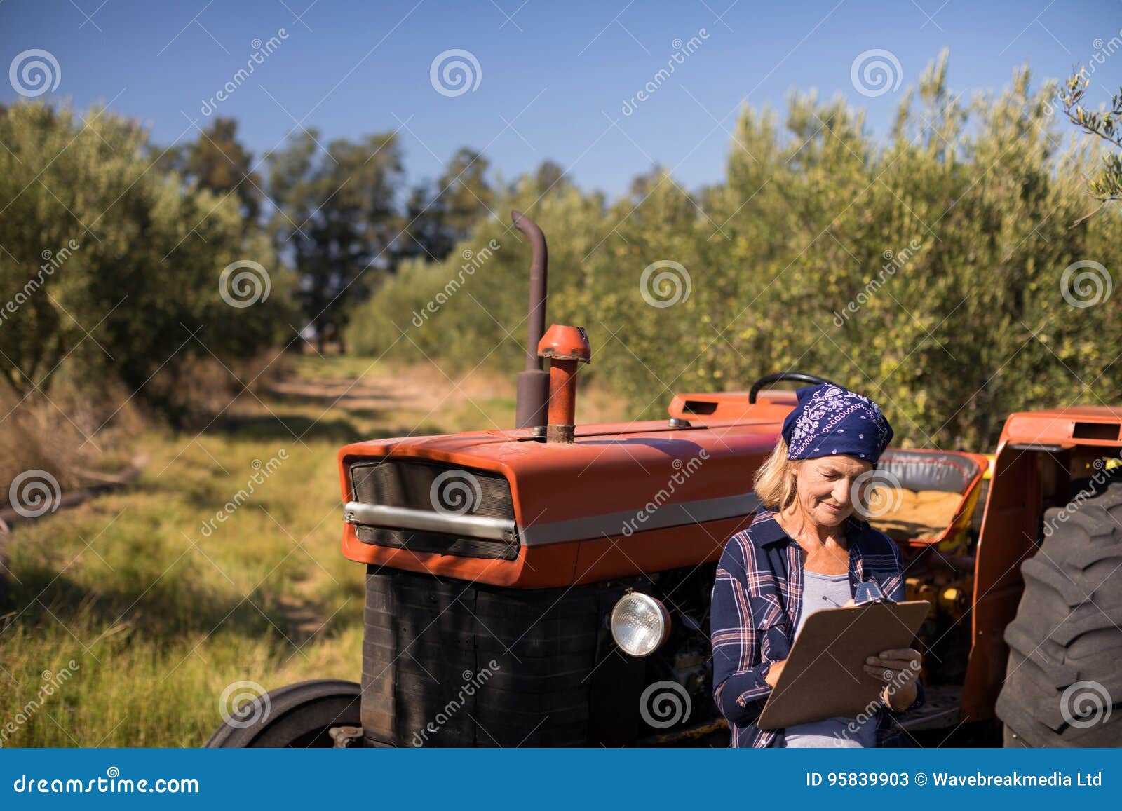 Woman Leaning on Tractor while Writing on Clipboard Stock Image - Image ...