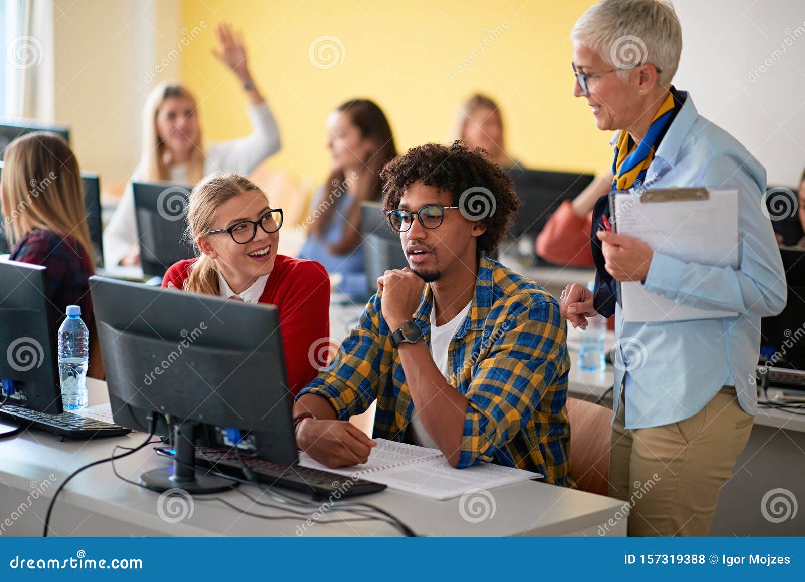 Woman Lecturer in Computer Class Assisting Multi-ethnic Student on ...