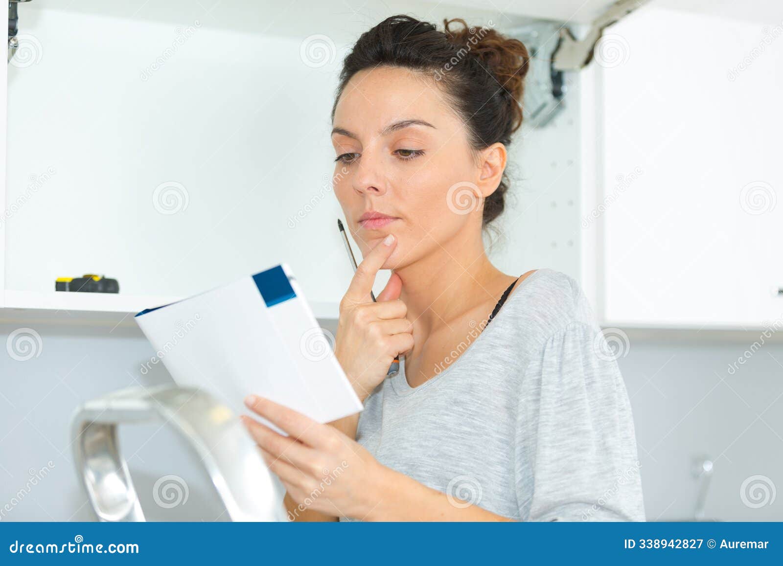 Woman Looking at Fitting Instructions for Kitchen Cupboard Stock Image ...