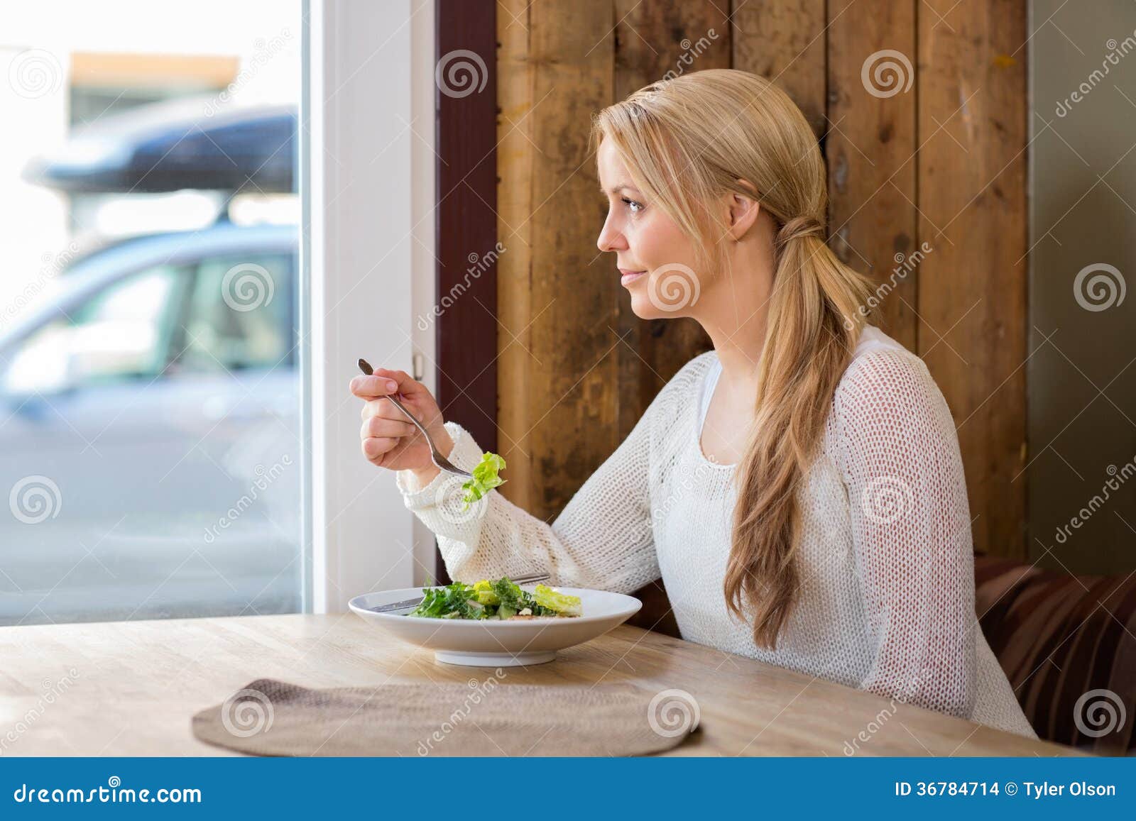 Woman Looking through Window while Eating Salad Stock Photo - Image of ...