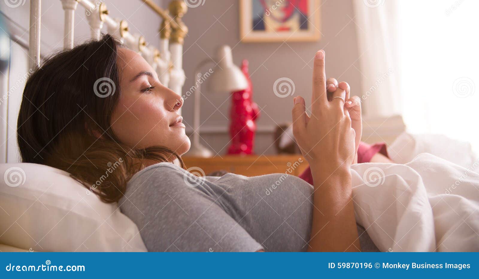 Woman Lying in Bed Checking Messages on Mobile Phone Stock Photo ...