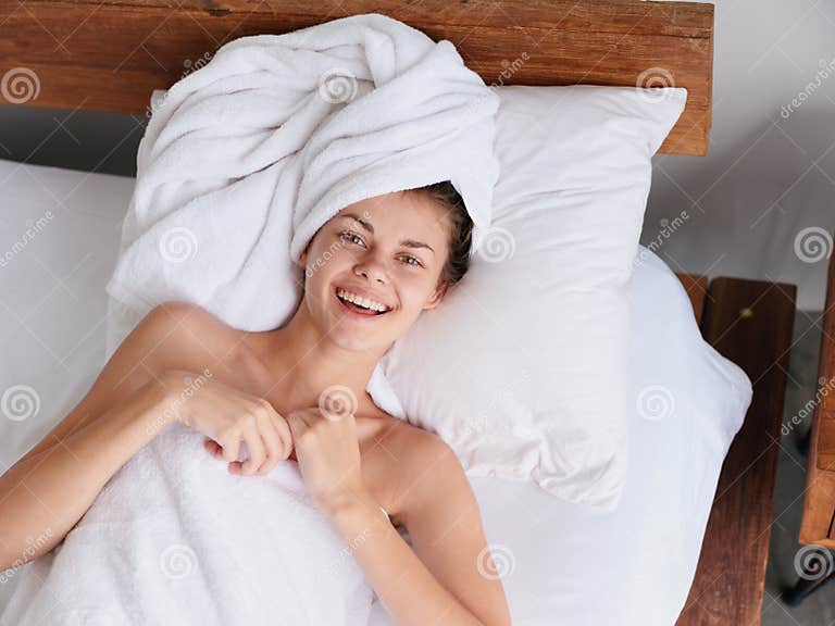 Woman Lying On Bed After Shower With Wet Hair With Towel On Her Head In