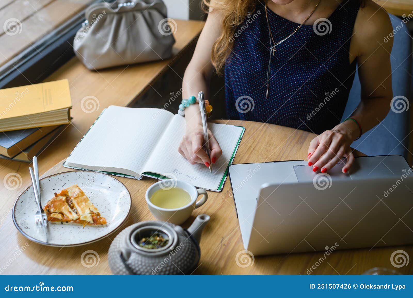A Woman Makes a Note in Her Notebook while Sitting in a Cafe Stock ...