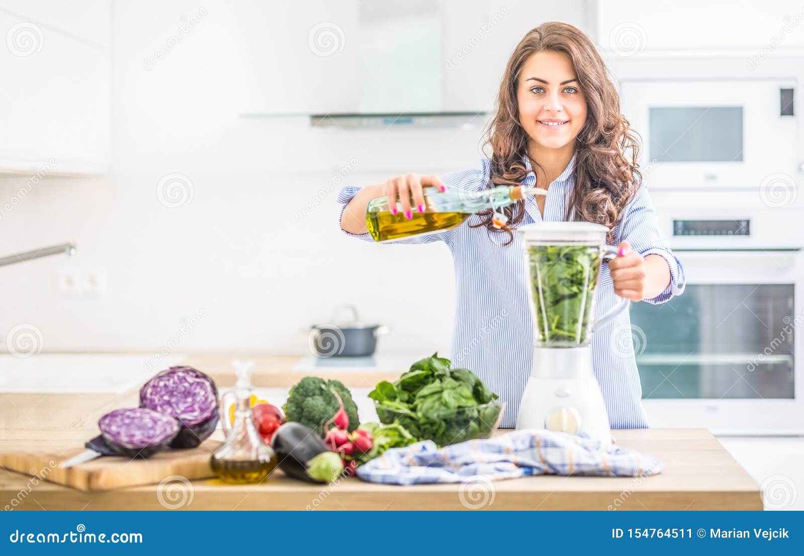 Woman Making Vegetable Soup Or Smoothies With Blender In Her Kitchen