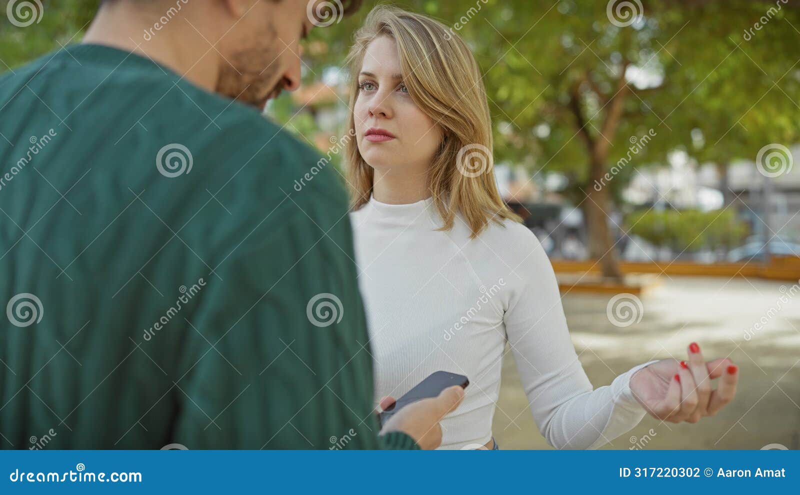 Woman and Man Having a Conversation Outdoors, with Her Holding a Mobile ...