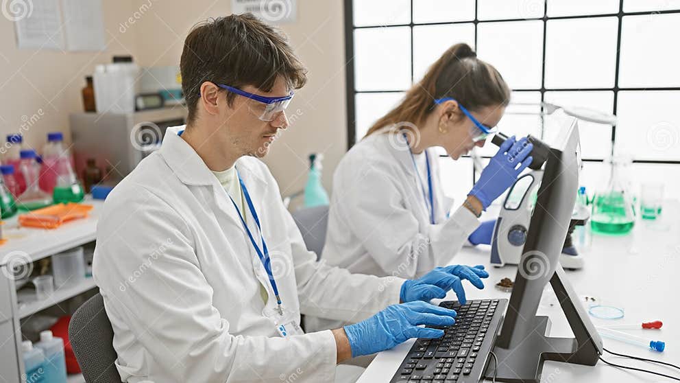 A Woman and Man in a Laboratory Working on Research with a Microscope and Computer, Depicting ...