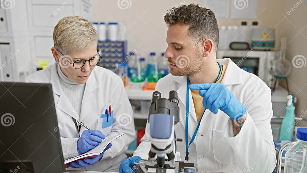 A Woman and a Man, Scientists, Collaborate in a Lab, Analyzing Data and ...