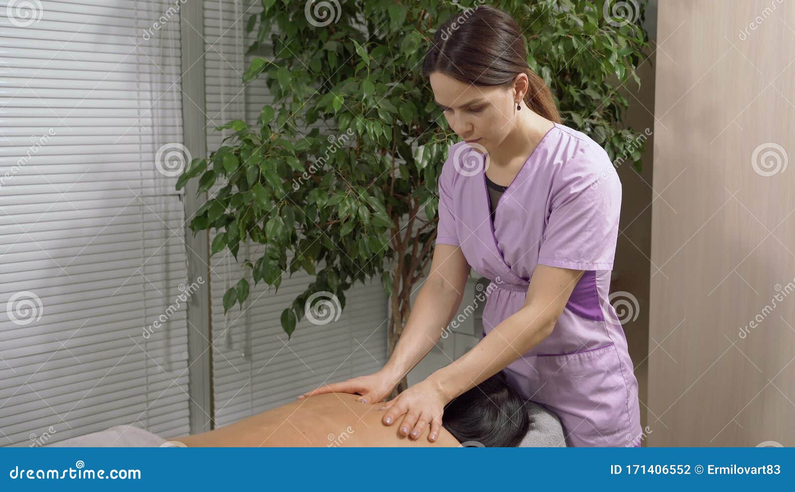 Woman Massage Therapist Doing Back Massage To A Young Brunette In A