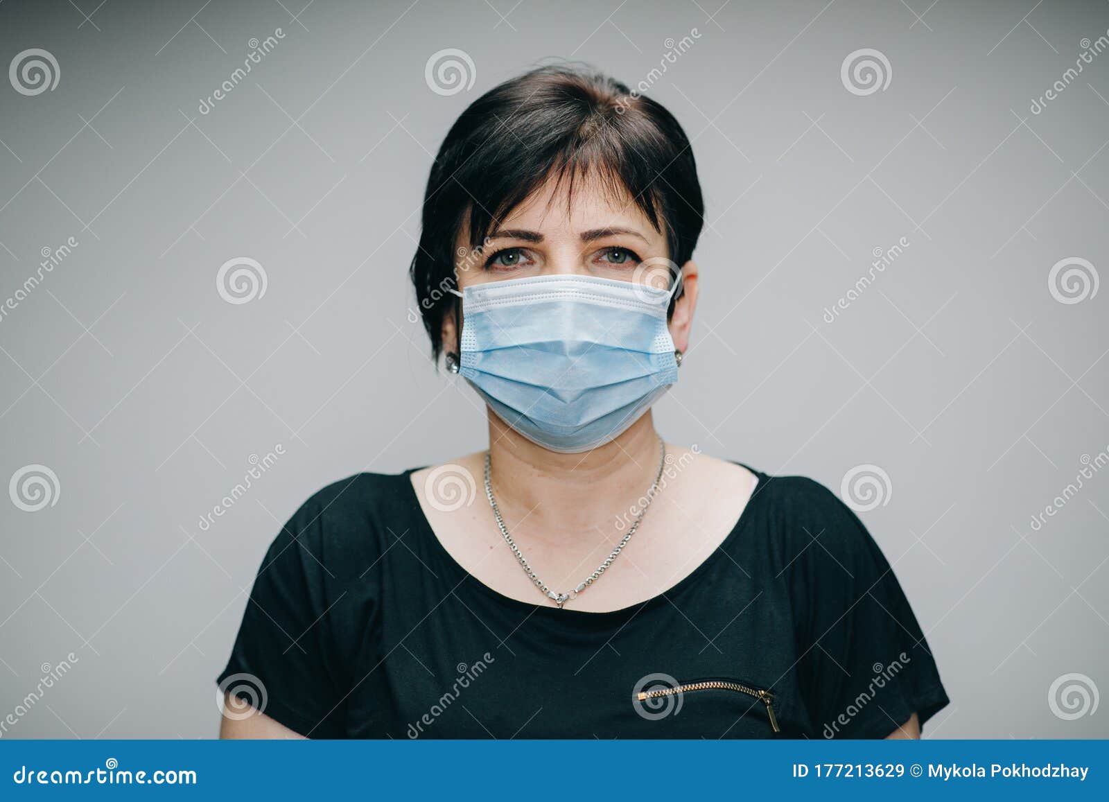 Woman In Medical Mask Breathes Deeply And Looking At Camera On Grey