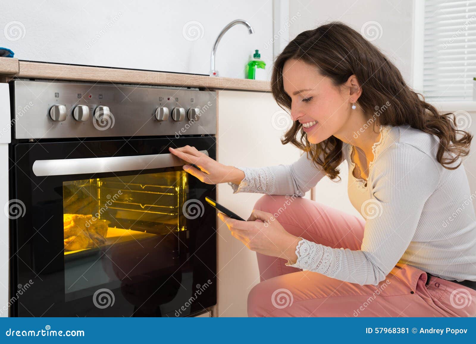 Woman with Mobile Phone while Cooking Chicken Stock Image - Image of ...