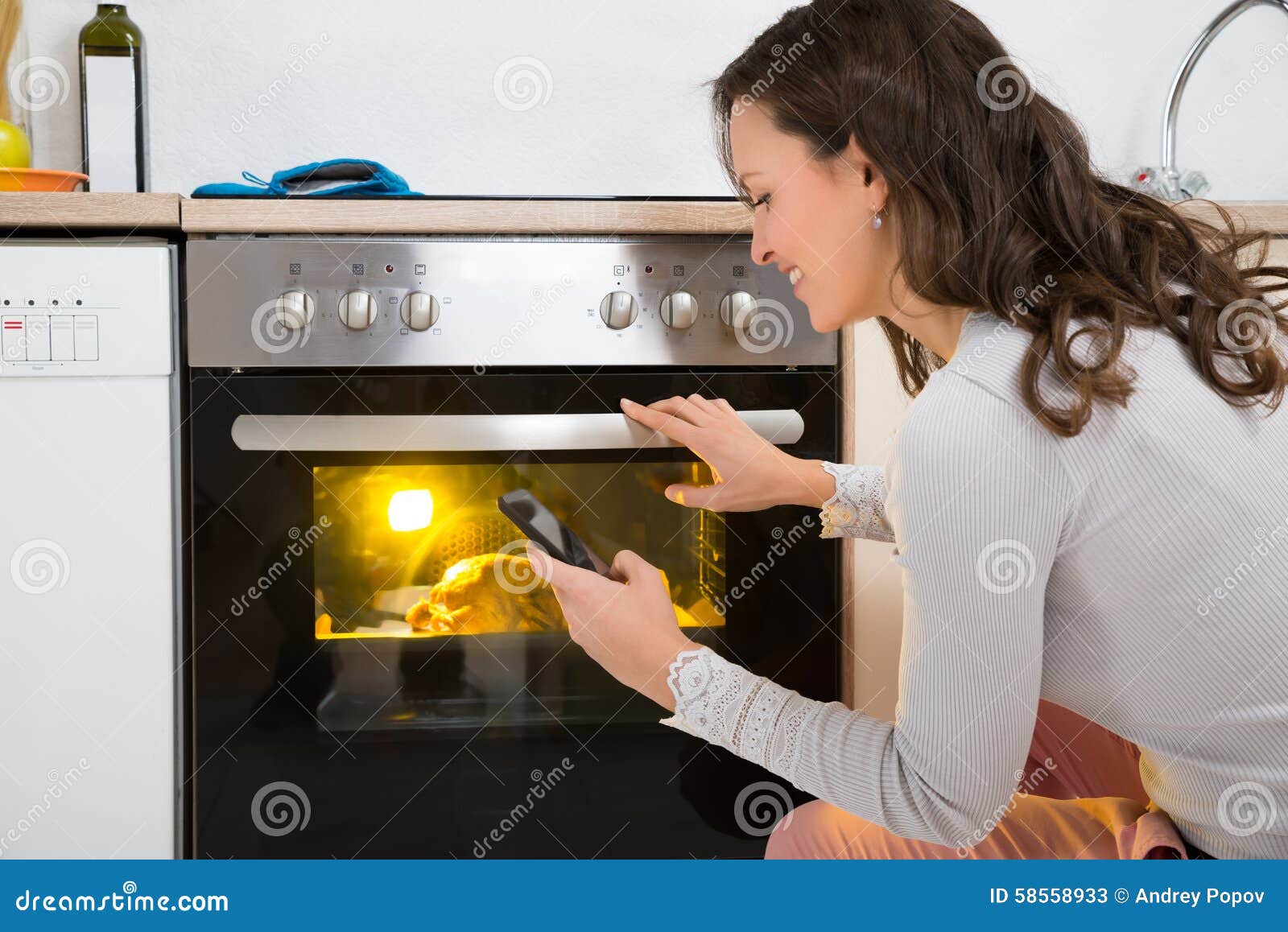 Woman with Mobile Phone while Cooking Chicken Stock Image - Image of ...