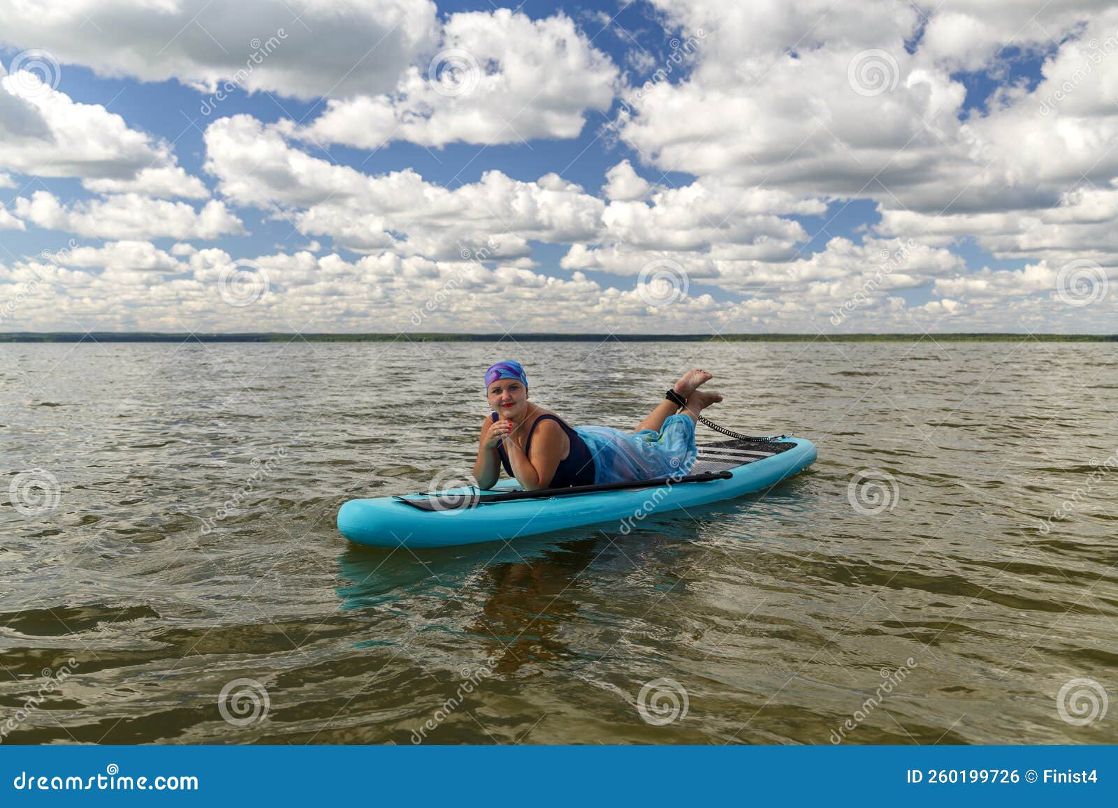 A Woman With A Mohawk In A Pareo Lies Sunbathing On A Sup Board In A