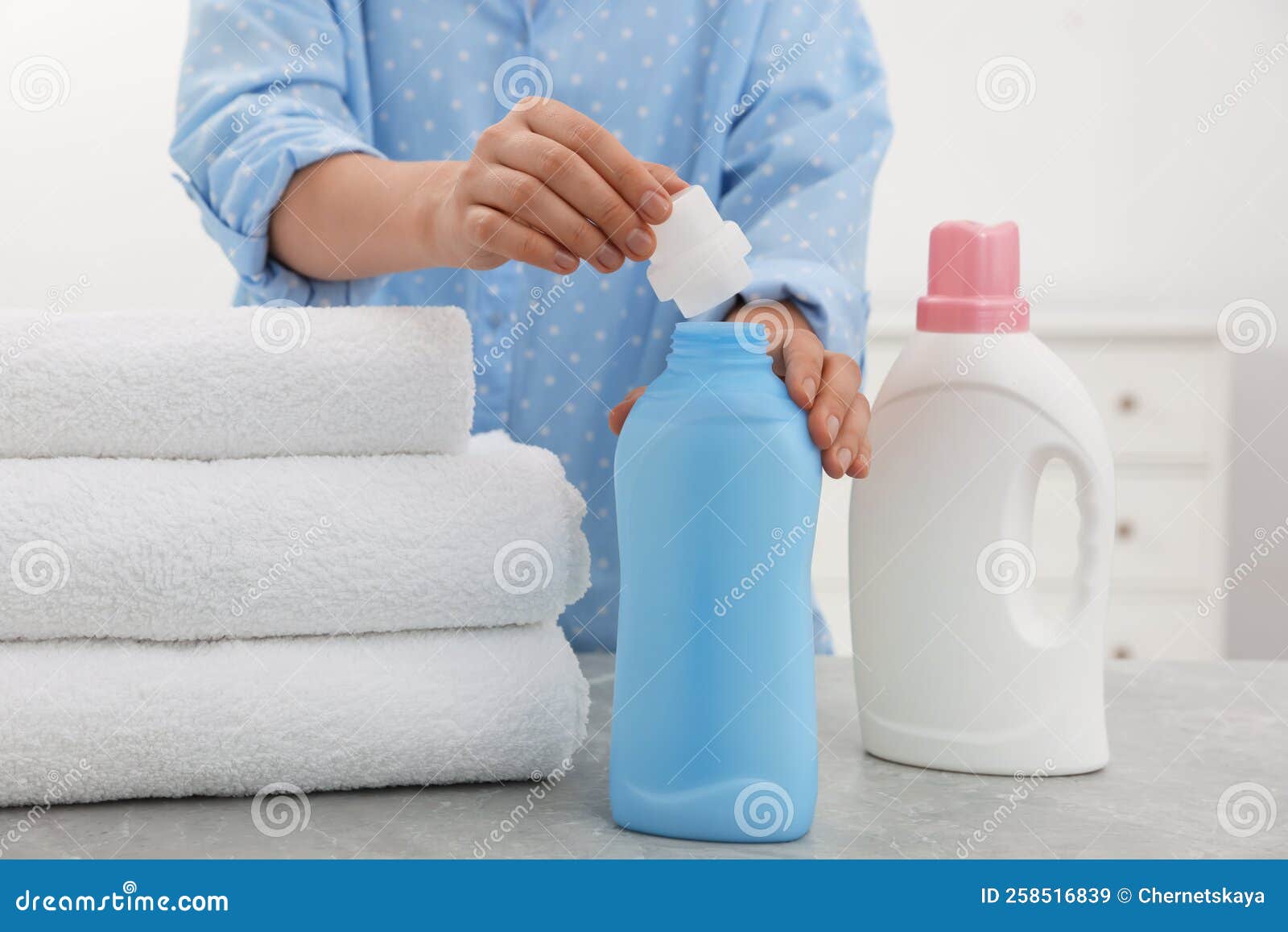 Woman Opening Bottle of Laundry Detergent at Light Grey Marble Table ...