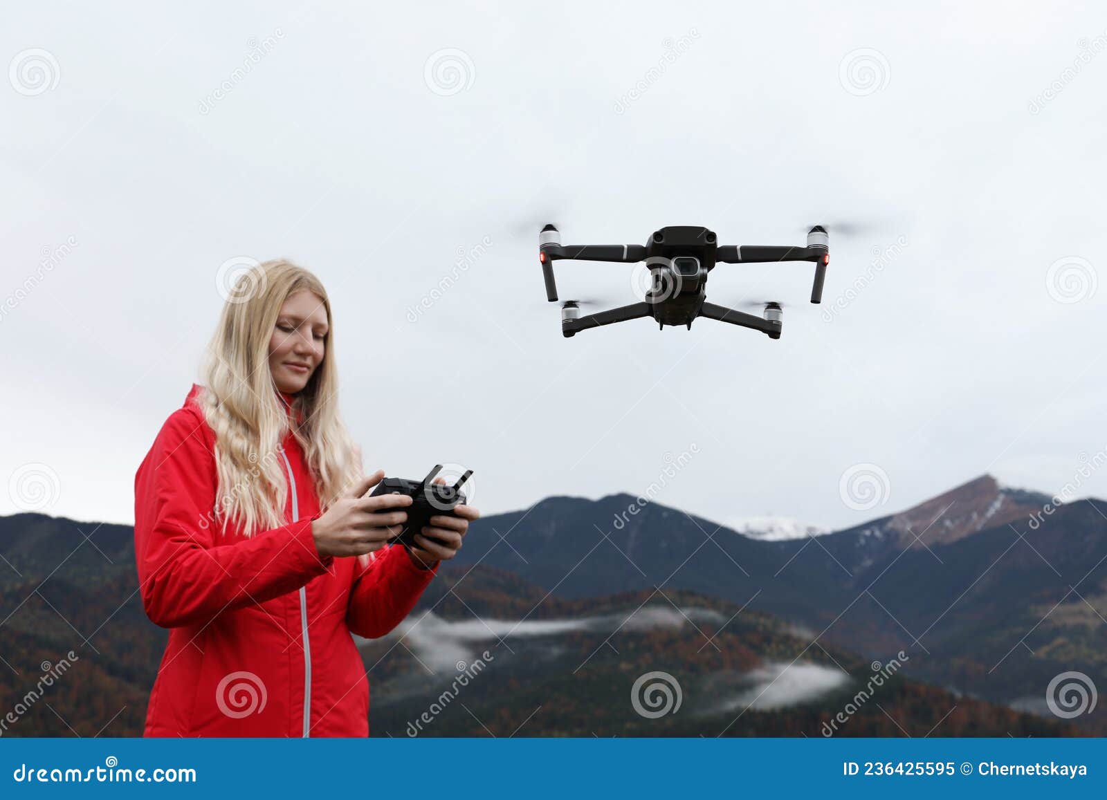 Young Woman Operating Modern Drone with Remote Control in Mountains ...