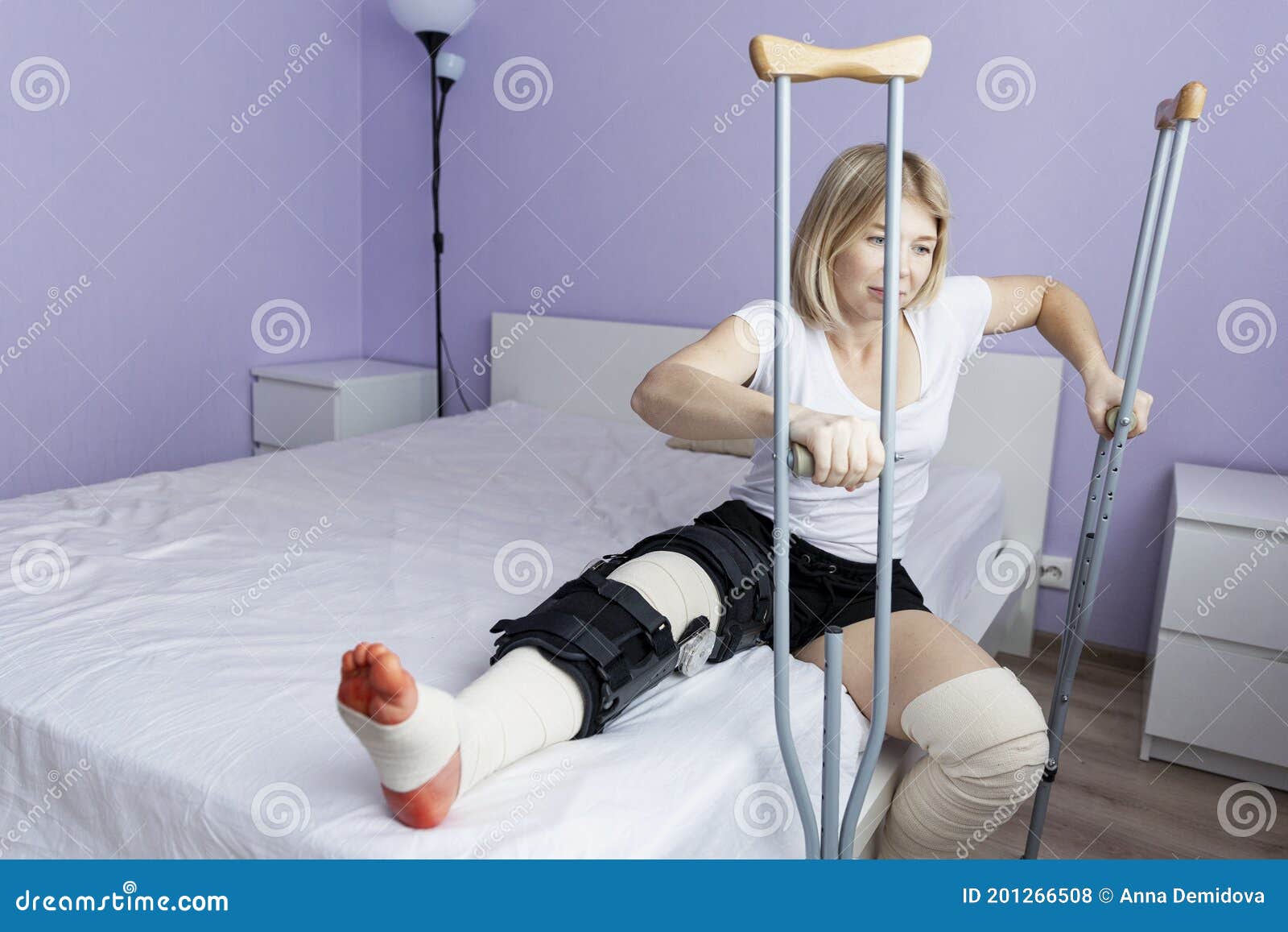 A Woman In An Orthosis And An Elastic Bandage After Leg Surgery Sits On