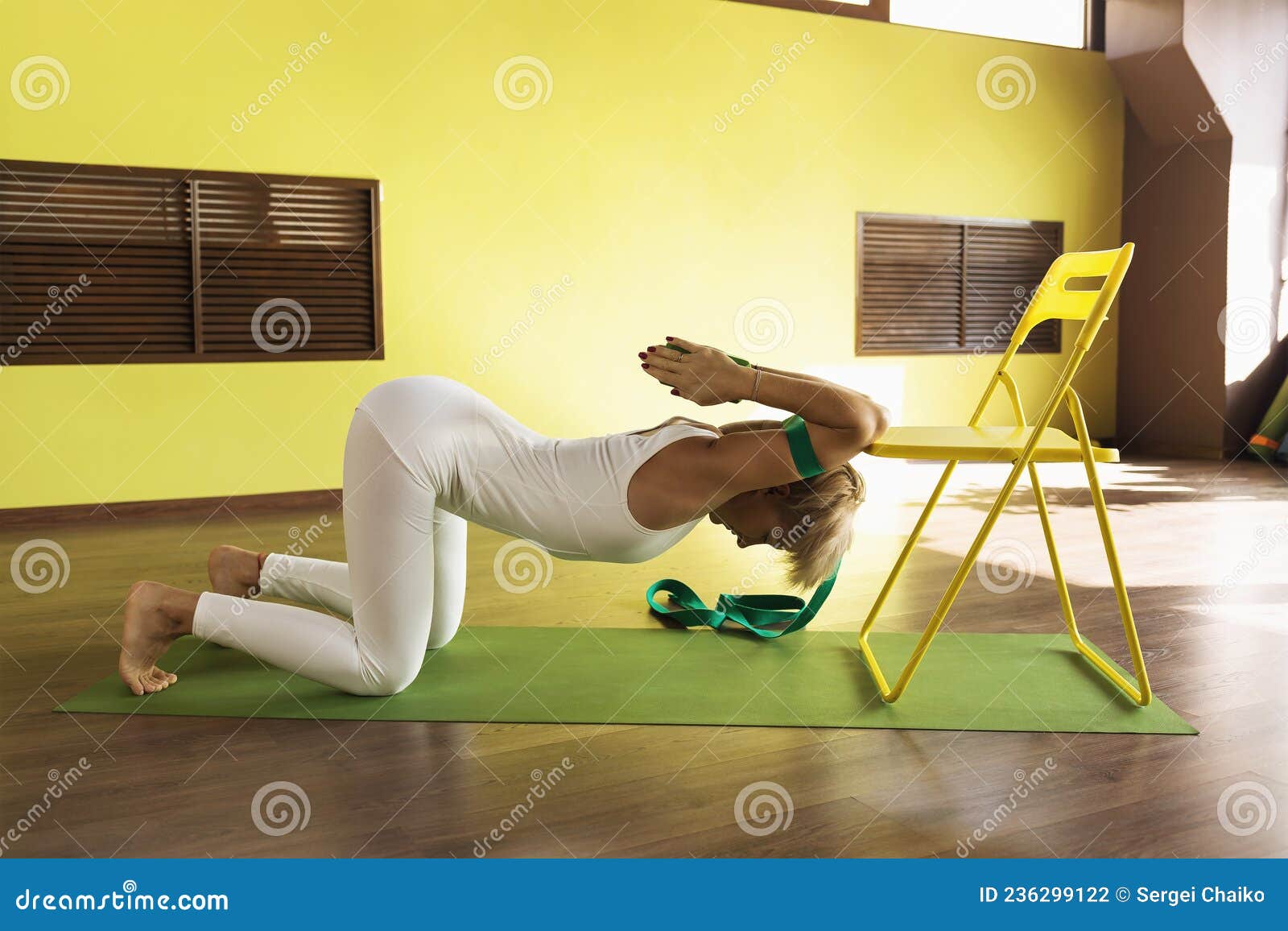 A Woman Performs a Spinal Muscle Stretching Exercise Using a Chair and ...
