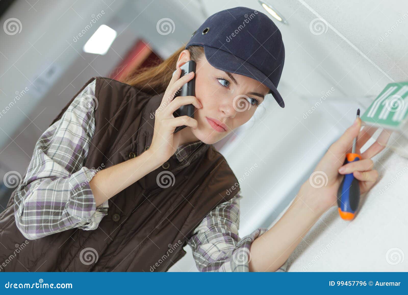 Woman on Phone while Fitting Exit Sign Stock Photo - Image of looking ...