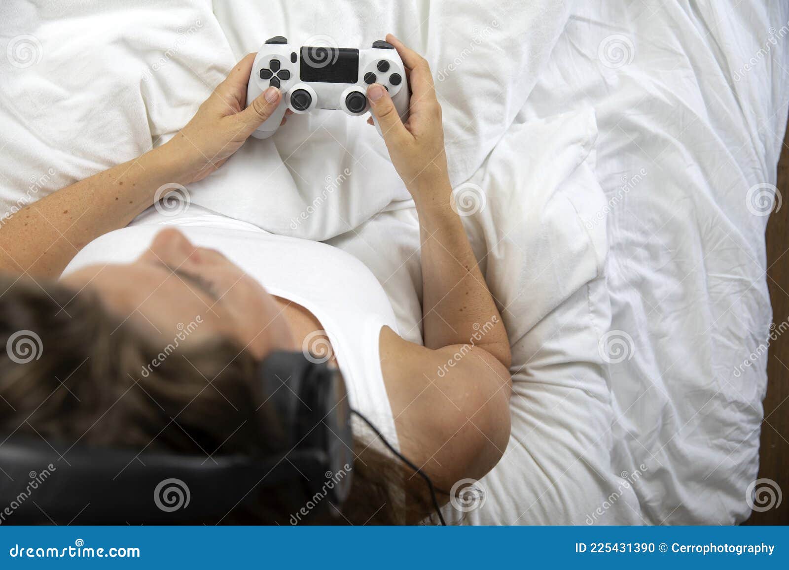 Woman Playing Video Games with Game Controller while Lying in Bed ...