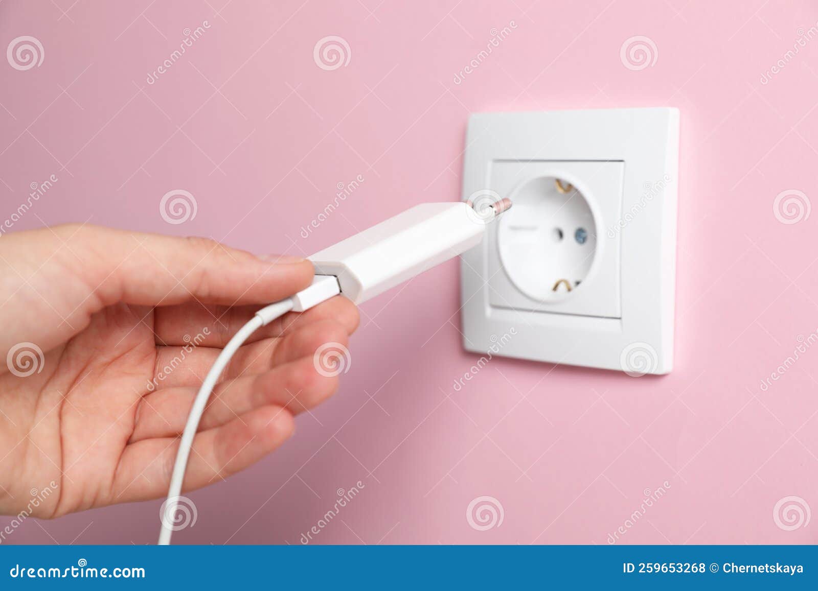 Woman Plugging Charger into Power Socket on Pink Wall, Closeup ...