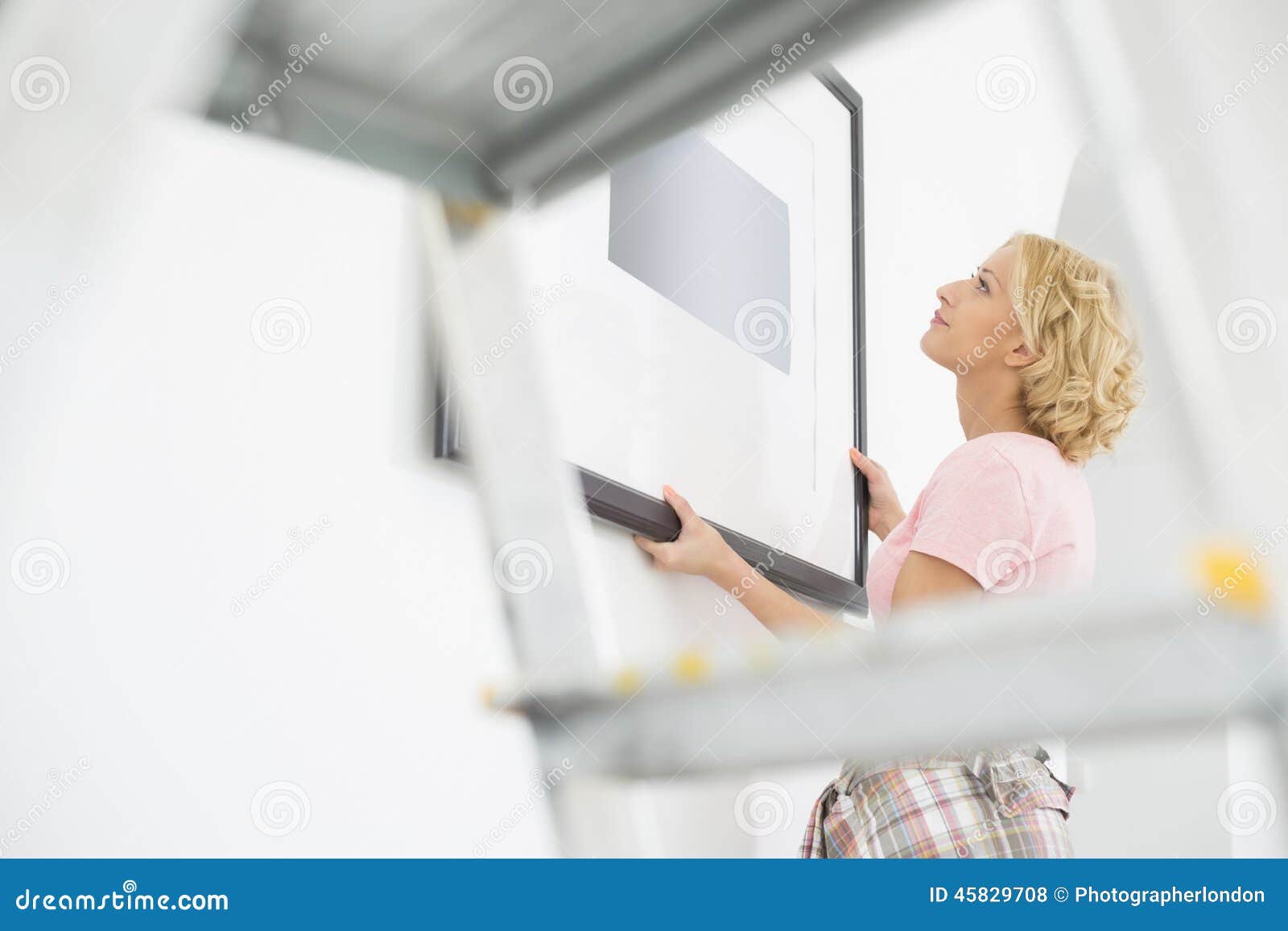Woman Positioning Picture Frame on Wall Stock Photo - Image of ...
