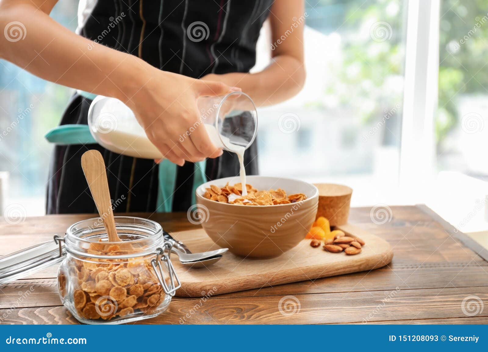 Woman Pouring Milk into Bowl with Corn Flakes at Table Stock Image ...