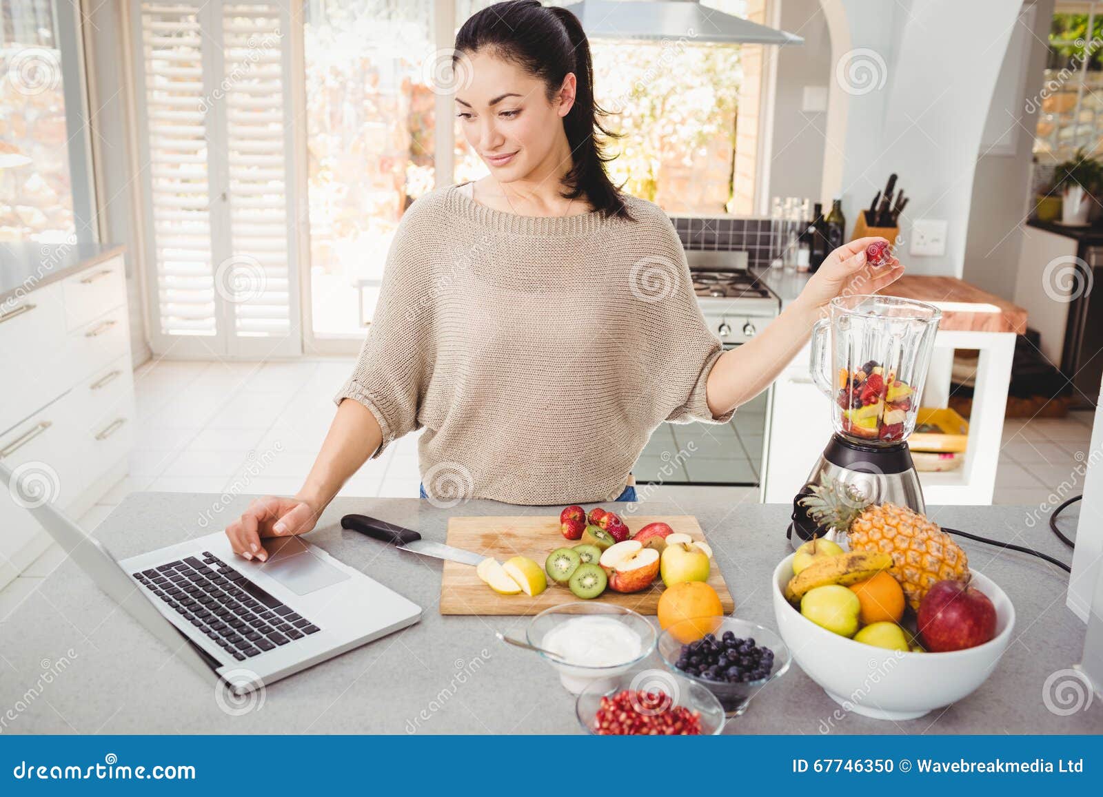 Woman Preparing Fruit Juice while Working on Laptop Stock Photo - Image ...