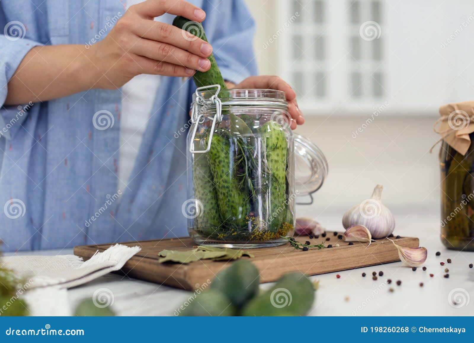 Woman Putting Cucumber into Pickling Jar at Table in Kitchen, Closeup ...