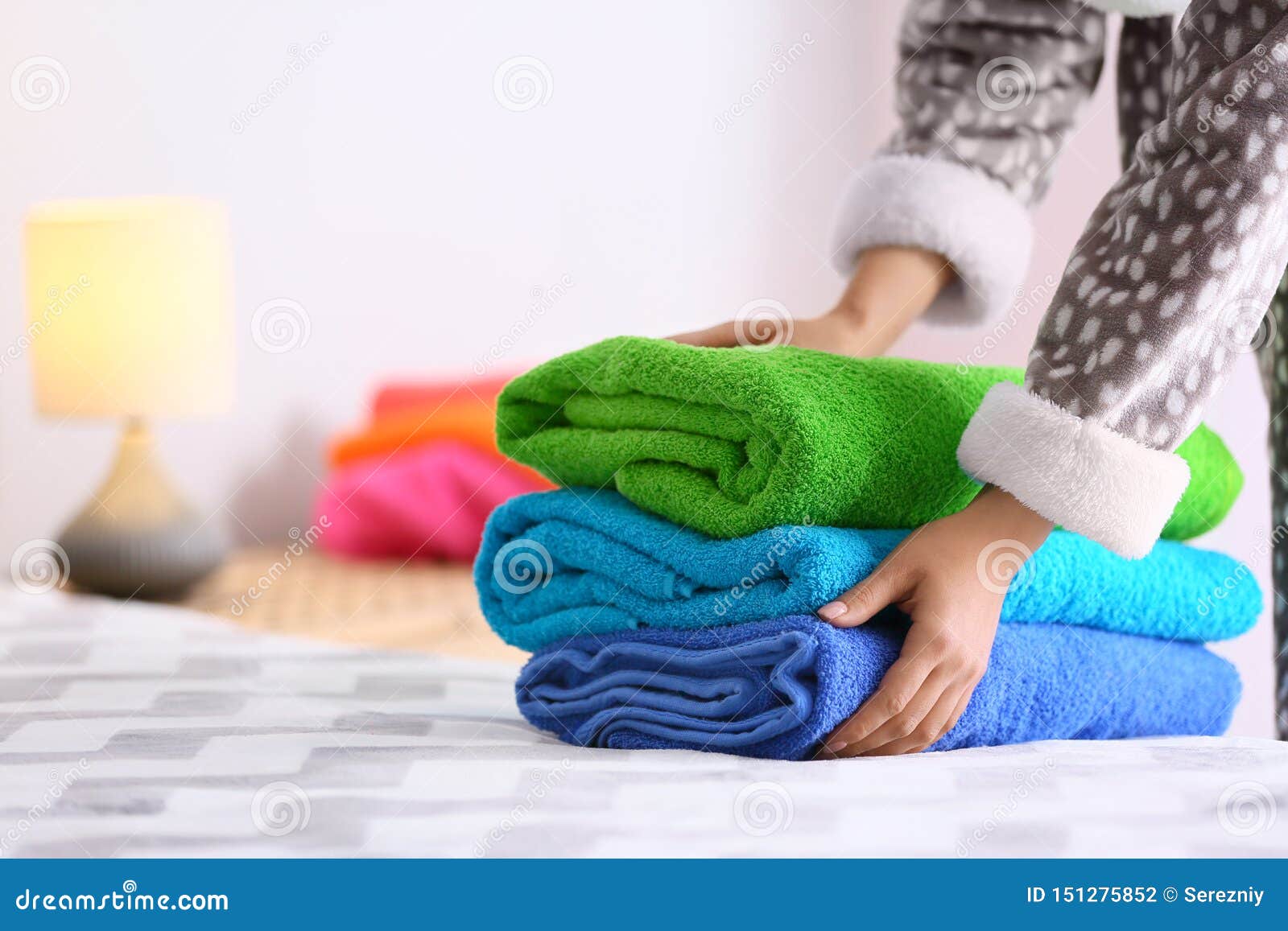 Woman Putting Stack of Clean Towels on Bed Stock Photo - Image of green ...