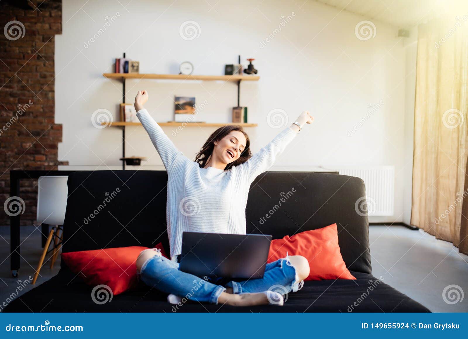 Young Woman Raising Her Hands Up on the Couch with Laptop at Home Stock ... Young Woman Raising Her Hands Up on the Couch with Laptop at Home Stock ...