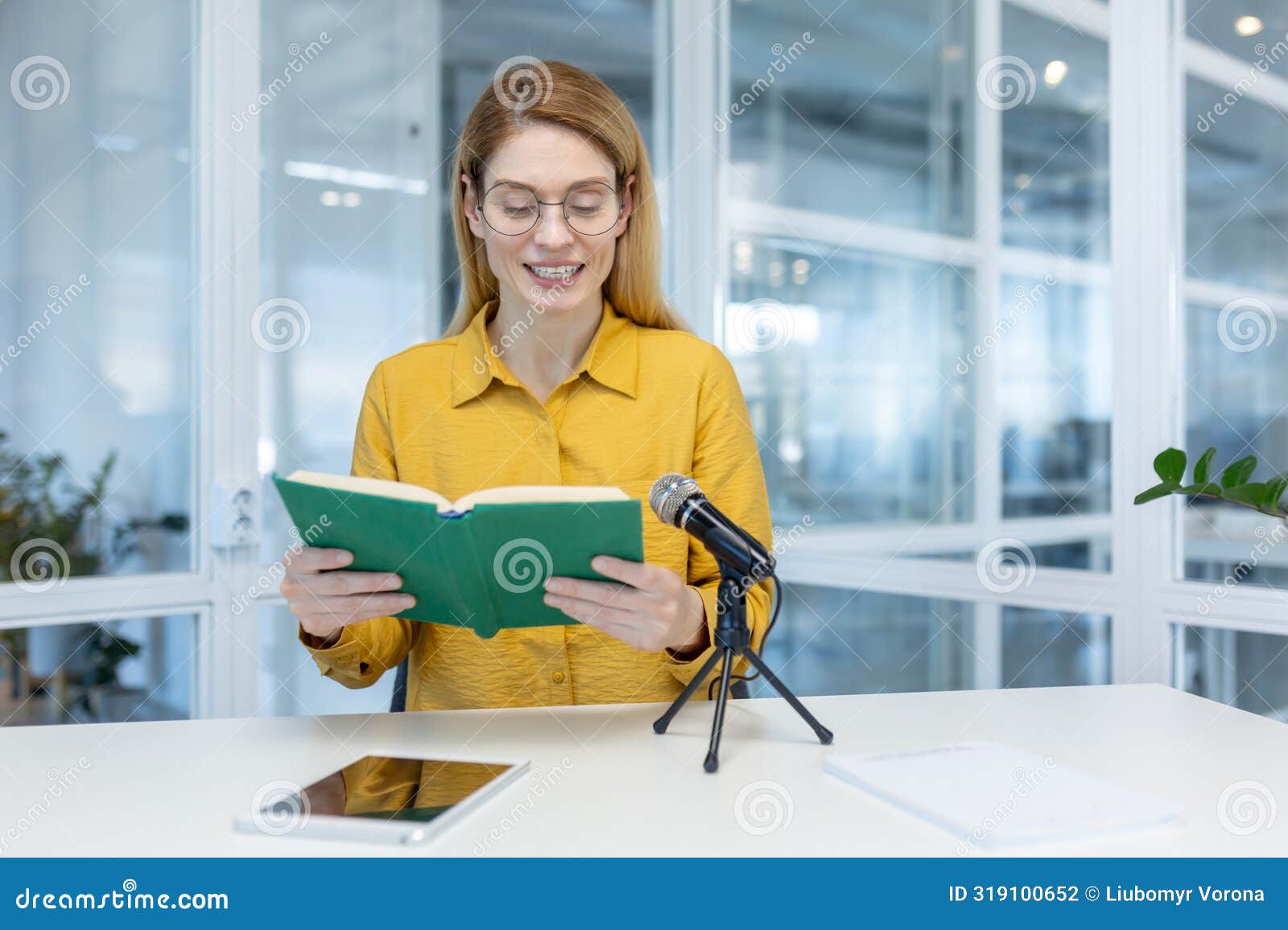 Woman Reading Book Aloud in Office with Microphone and Tablet Stock ...